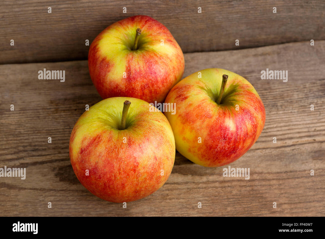 Three red apples on wooden background, natural light Stock Photo - Alamy