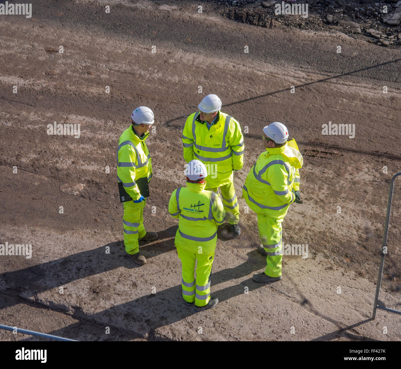 Four construction workers talking to each other wearing the correct ...