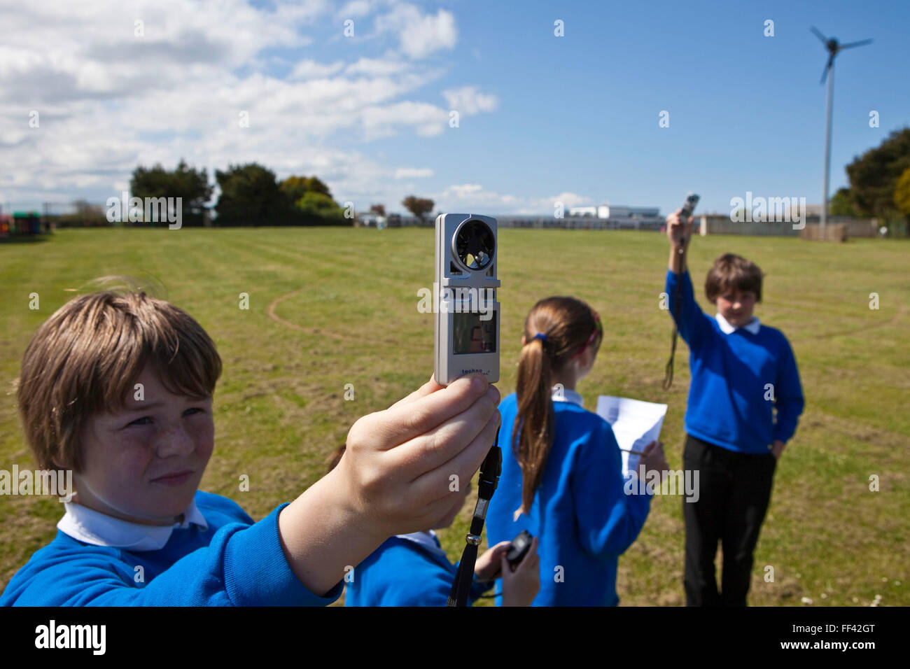 Primary school children measuring wind speeds with anemometers to help ...