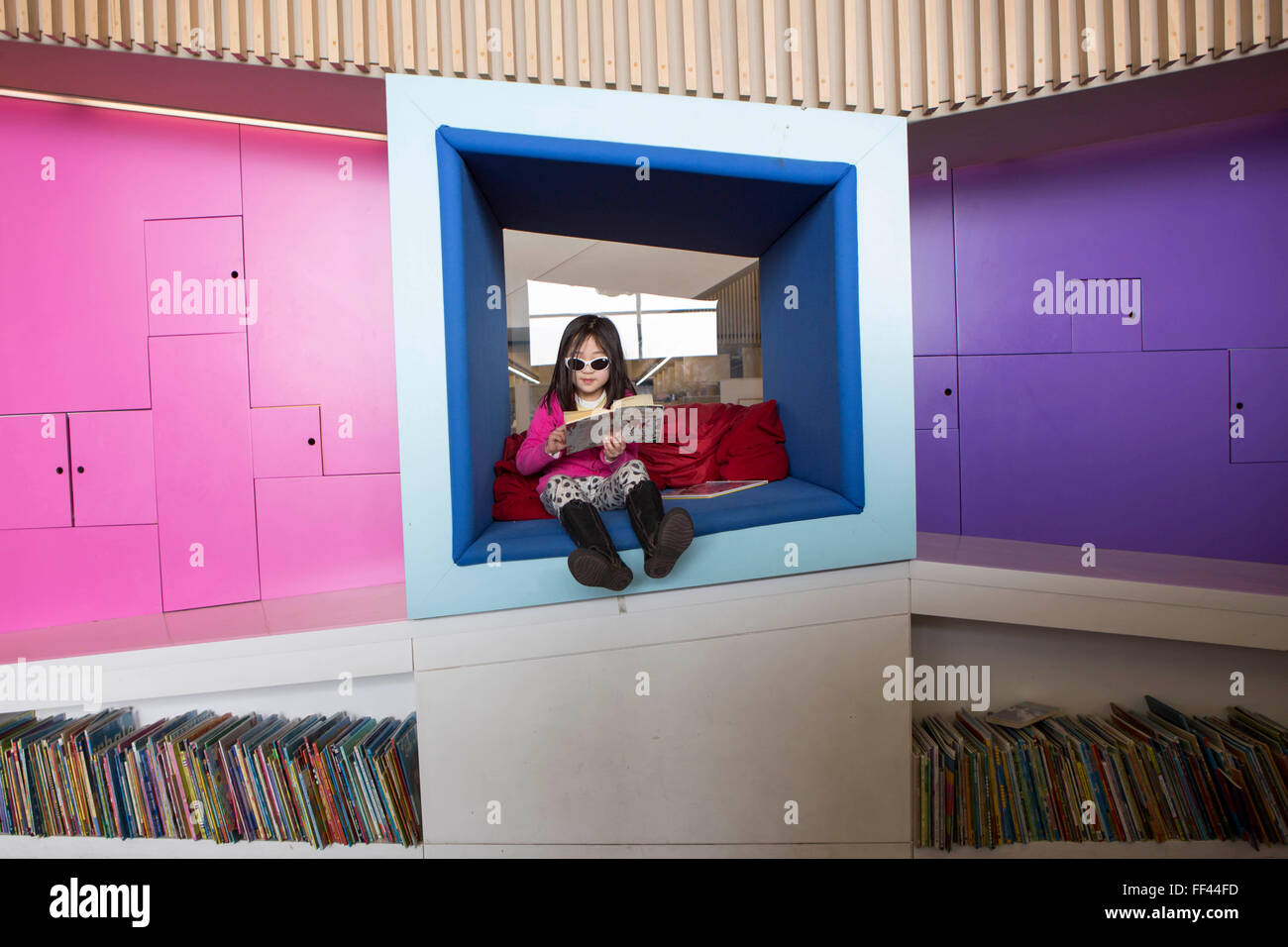 A young girl reading inside the library of the Hive in Worcester, UK ...