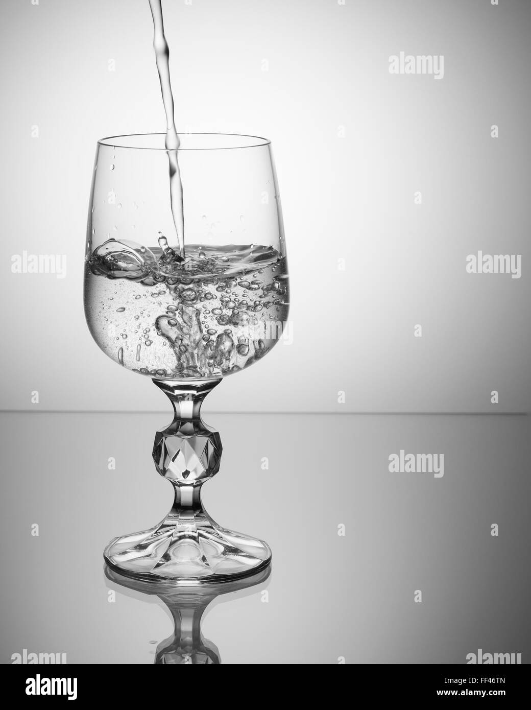 Glass with a drink pouring in and splashing out Stock Photo - Alamy