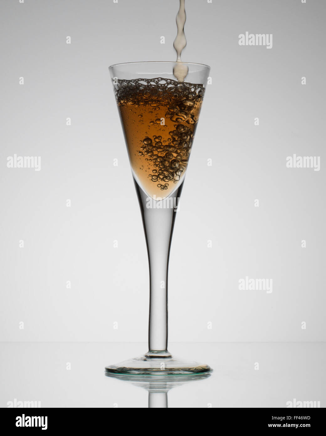 Glass with a drink pouring in and splashing out Stock Photo - Alamy