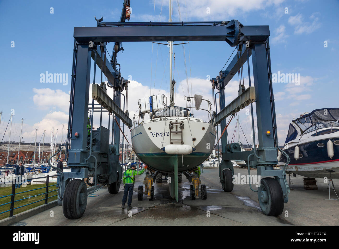 A large yacht is carefully placed upon a boat cradle lift in a marina ...