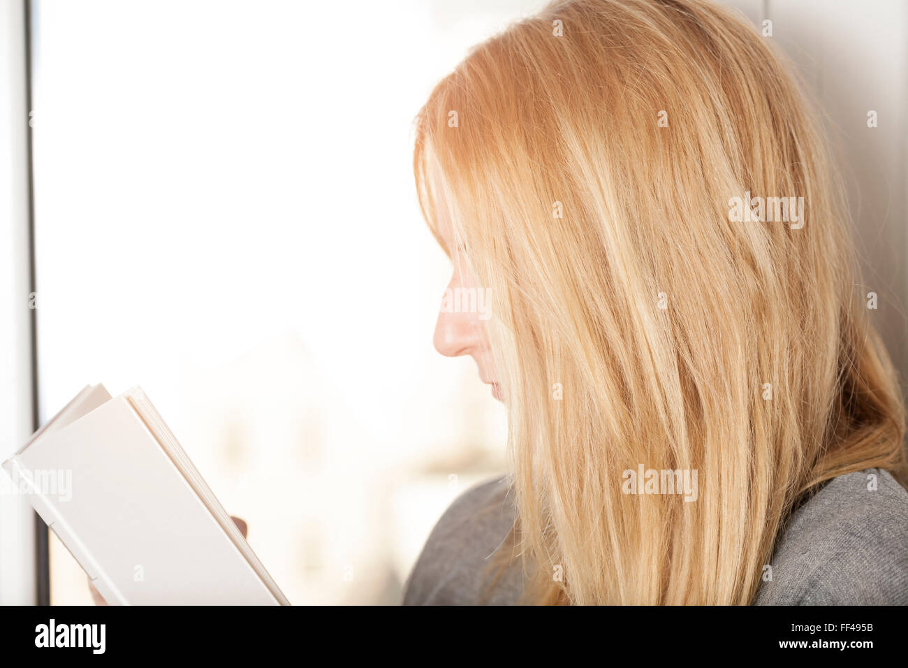 woman reading a book on window sill Stock Photo - Alamy