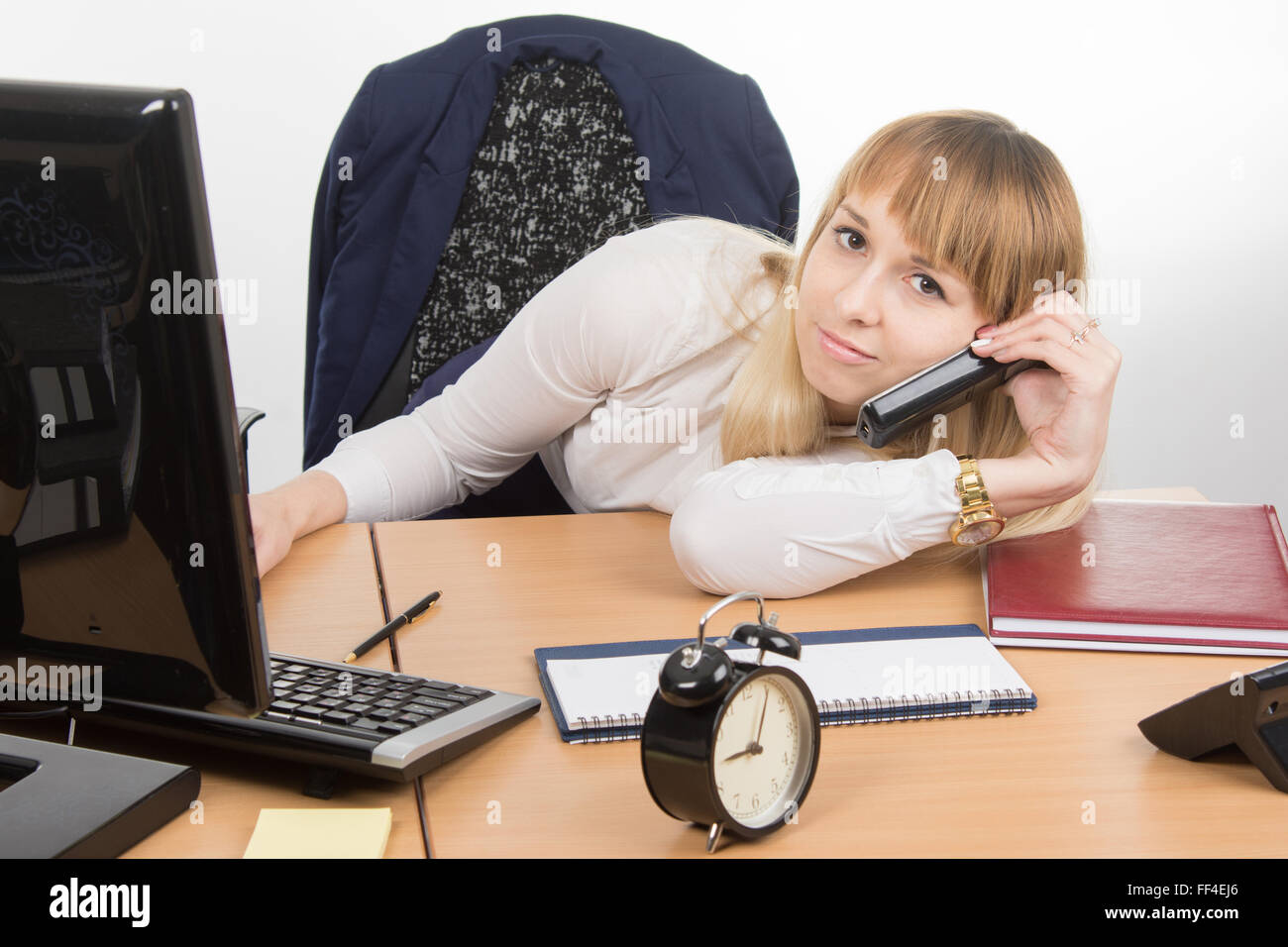 Tired office employee lying on the desk talking on the phone and looked ...