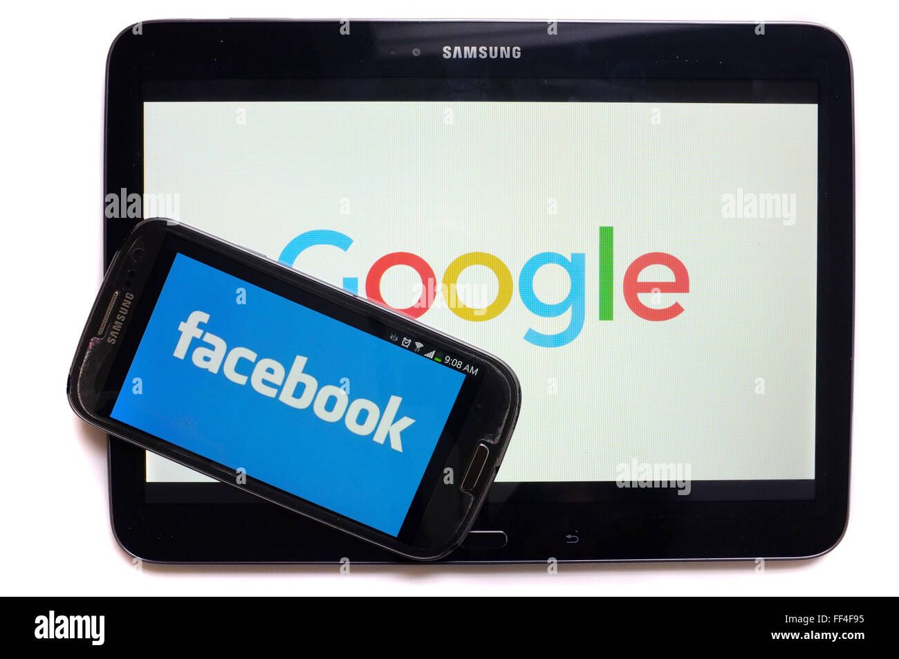 The Facebook logo on a smartphone and Google on a tablet photographed ...