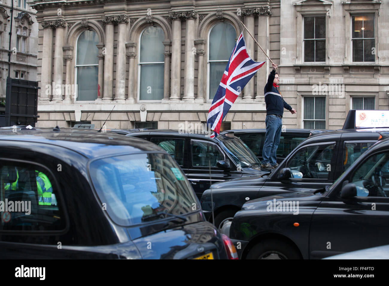London, UK. 10th February 2016. A black cab driver waves a Union Jack ...