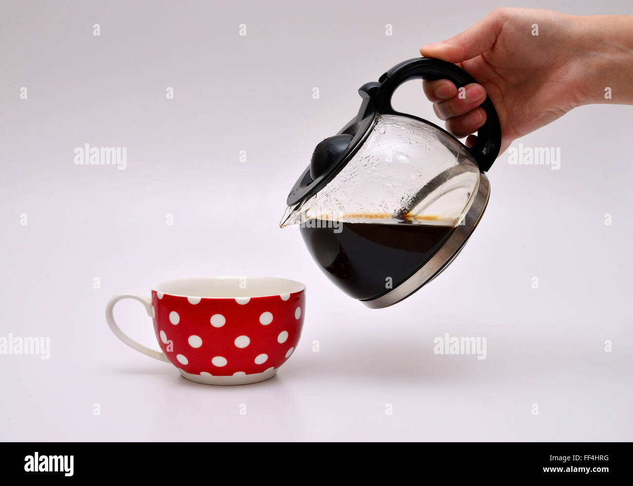 pouring coffee on a red cup with white dots isloated Stock Photo - Alamy