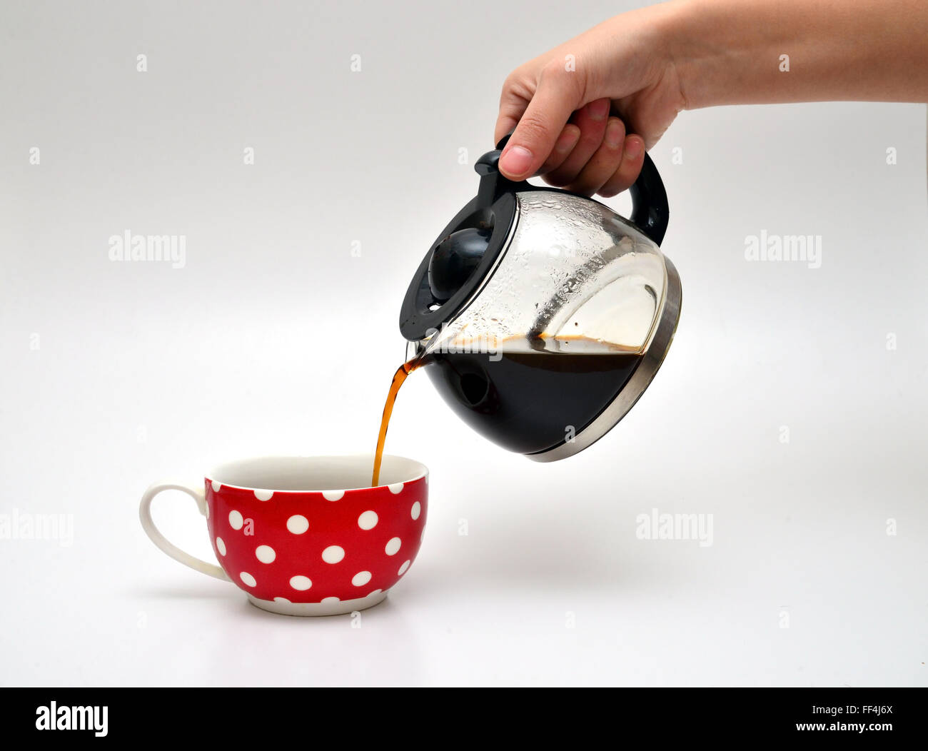 pouring coffee on a red cup with white dots isloated Stock Photo - Alamy