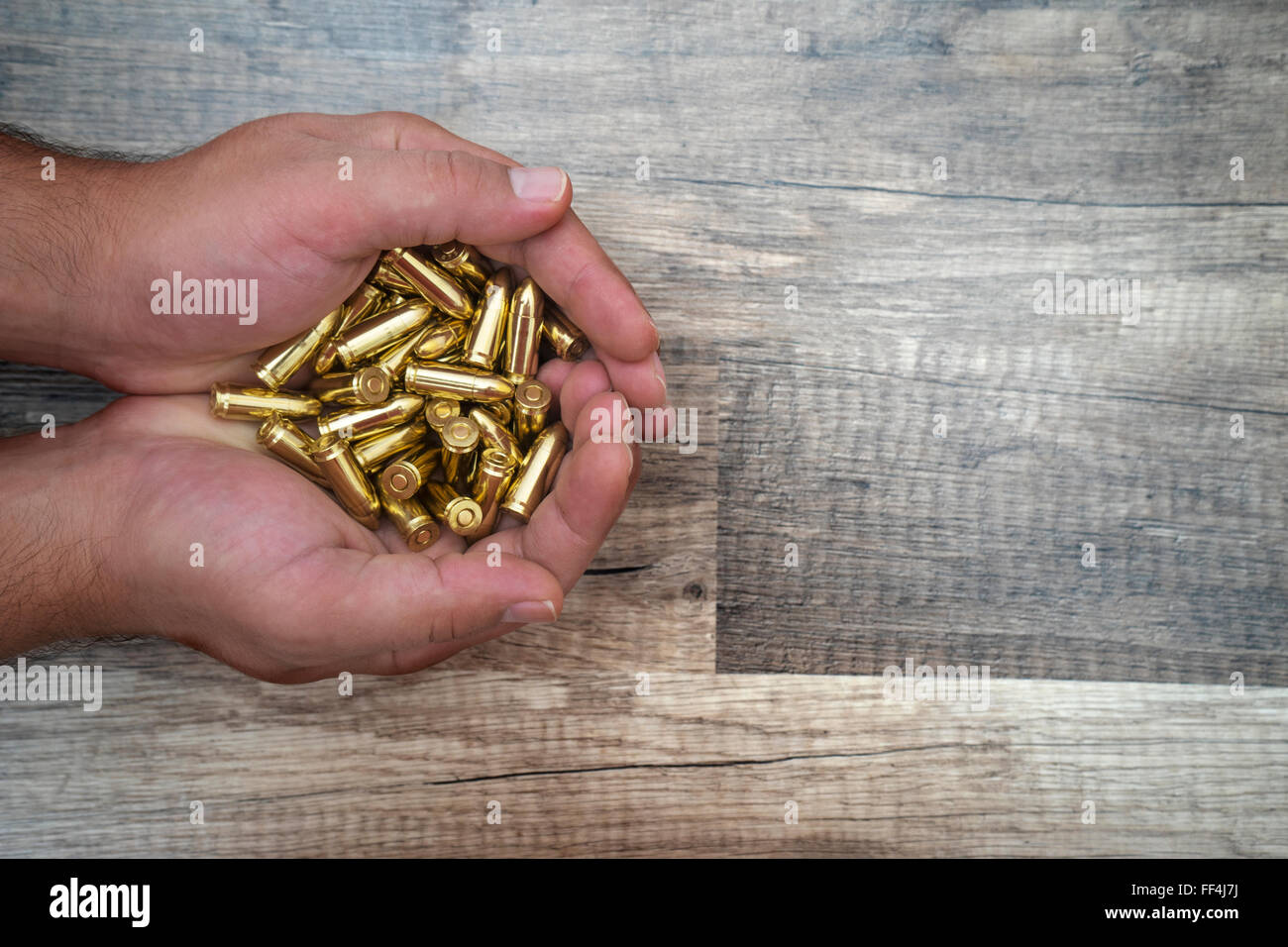 Many bullets into man's masculine hands, with wooden background Stock ...