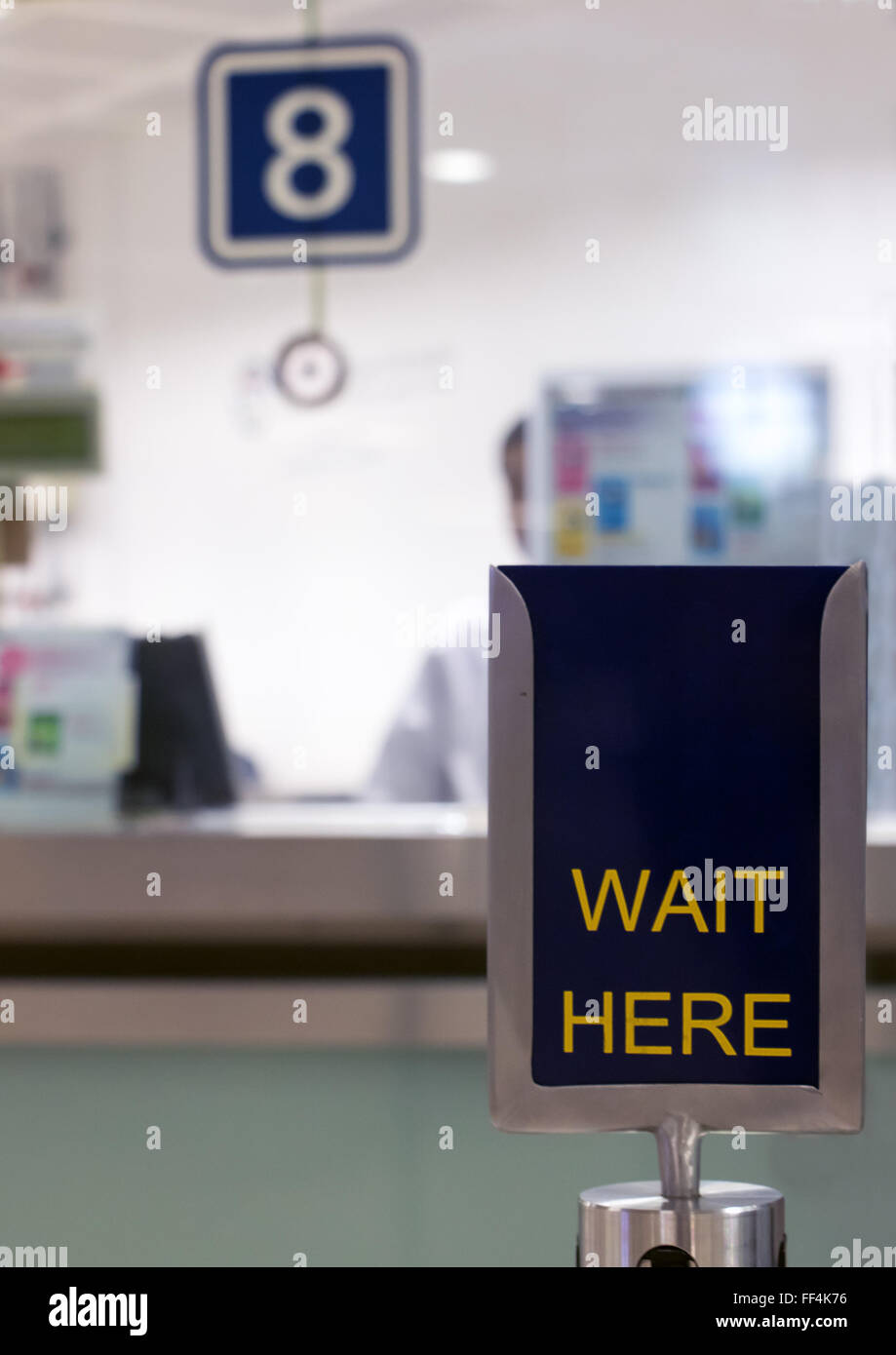 sign with text WAIT HERE before counter Stock Photo - Alamy