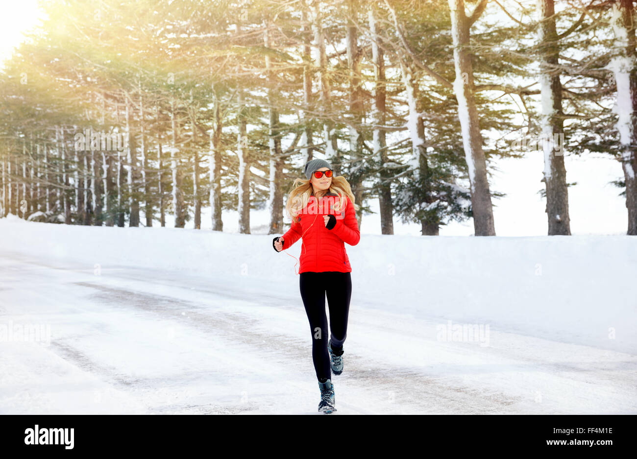 Woman running in the winter park, doing exercise in cold frosty morning ...