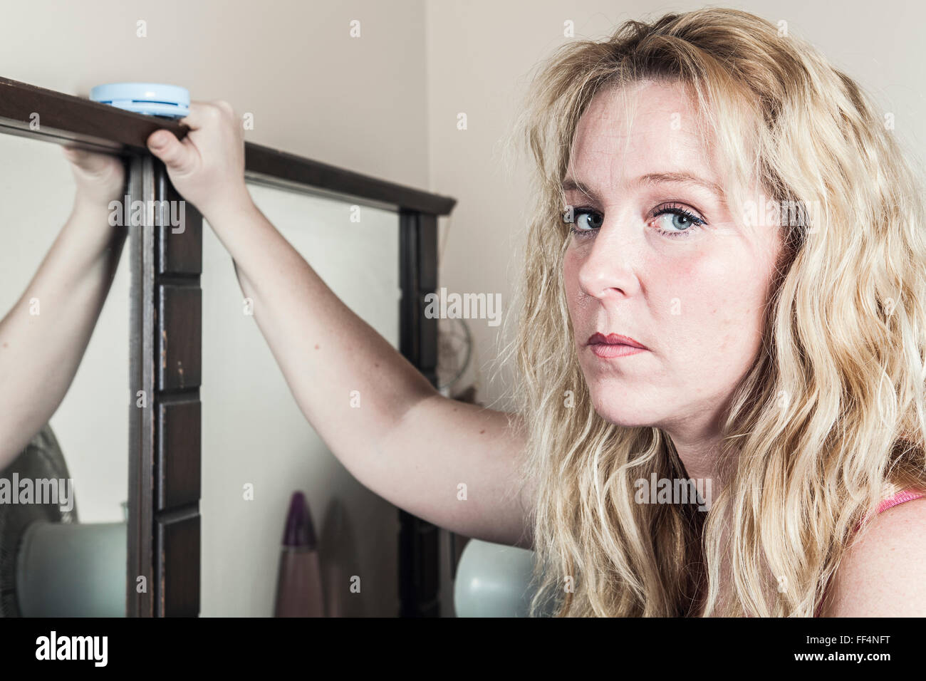 Young sad woman looking in the mirror Stock Photo - Alamy