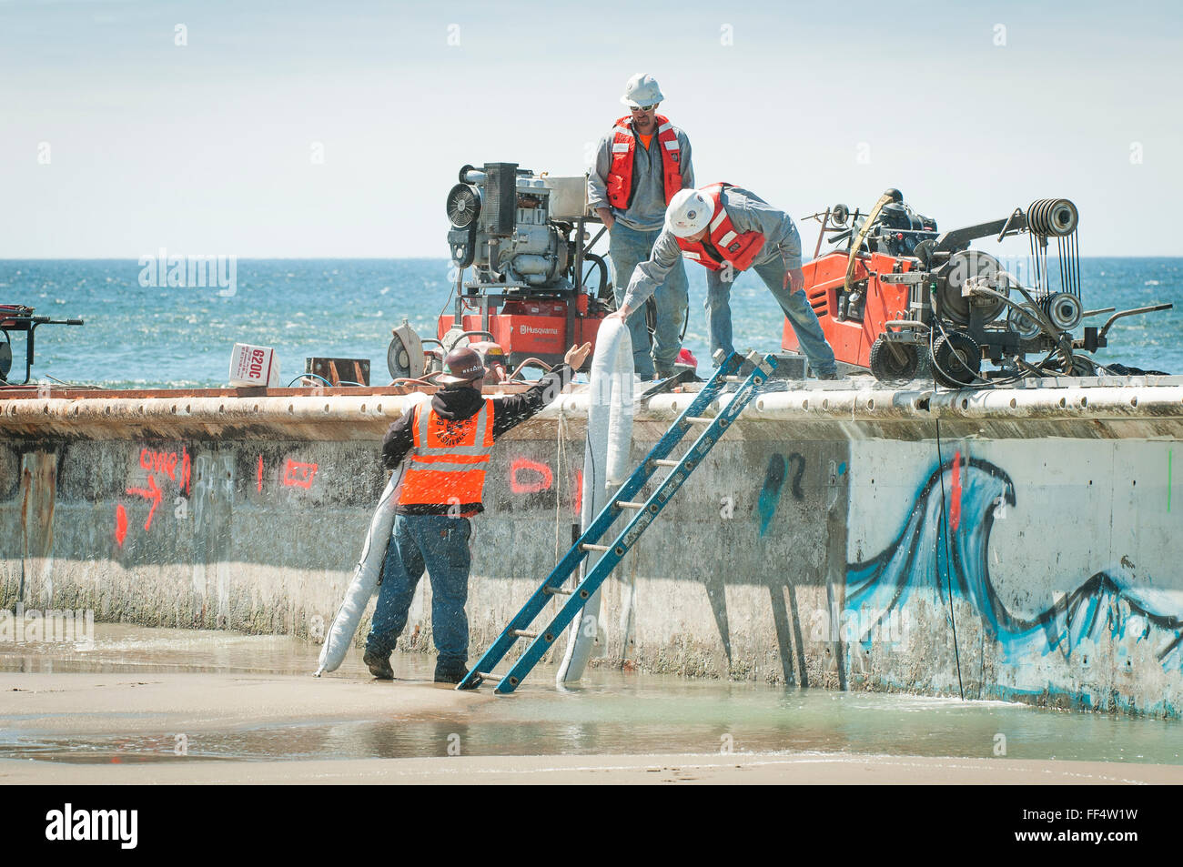 Workers remove a cement floating boat dock that had drifted across the ...