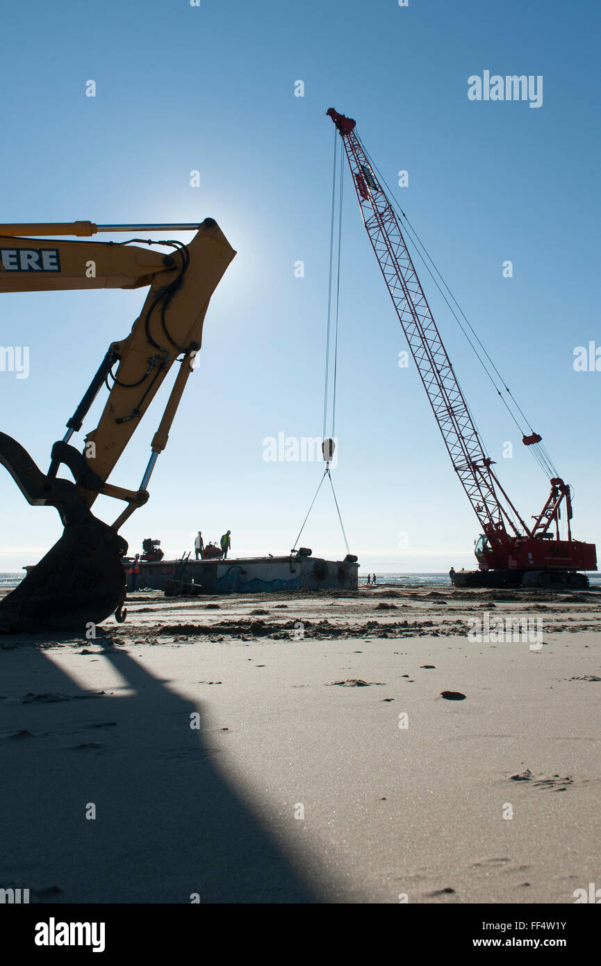 Workers remove a cement floating boat dock that had drifted across the ...
