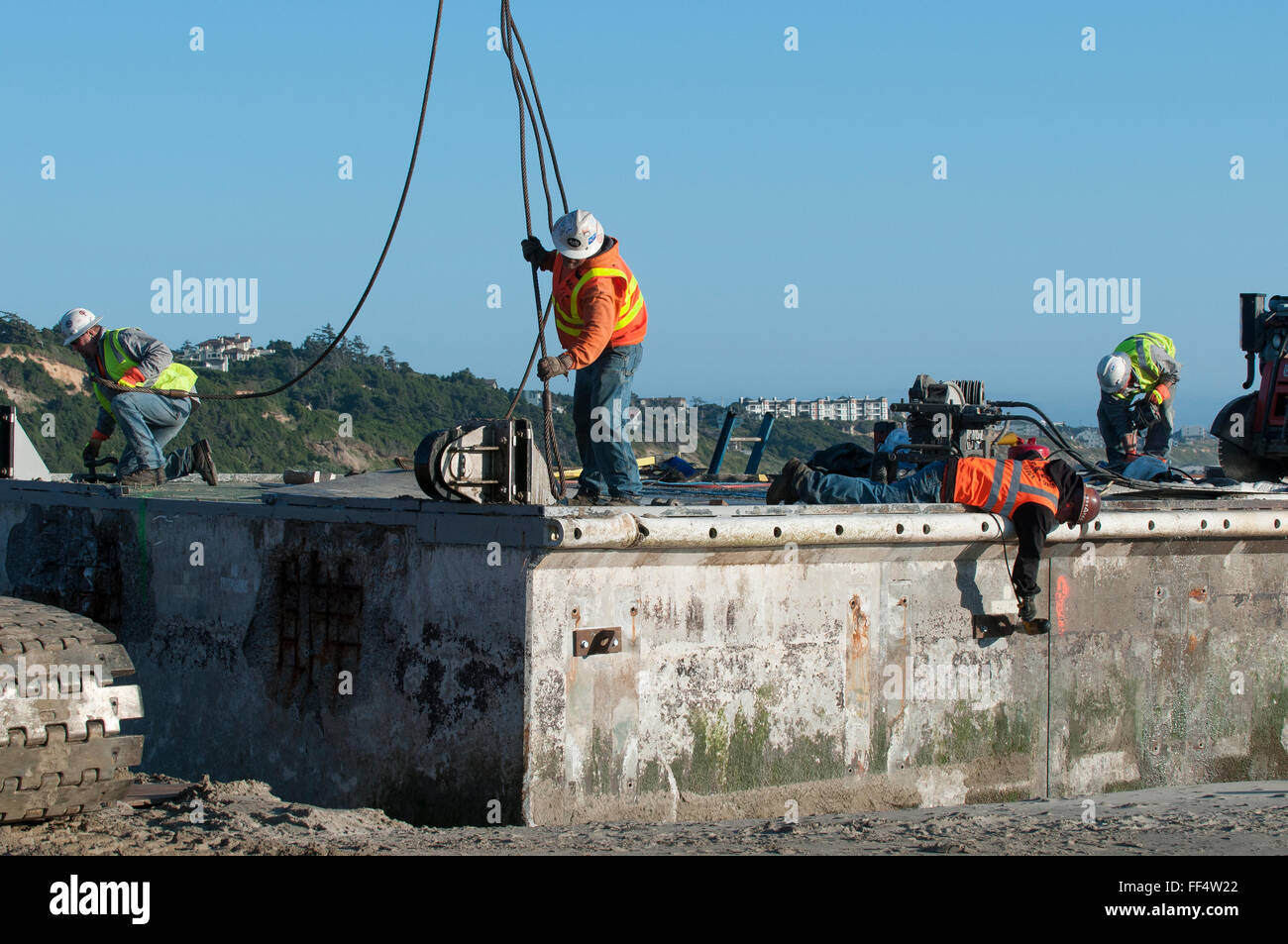 Workers remove a cement floating boat dock that had drifted across the ...