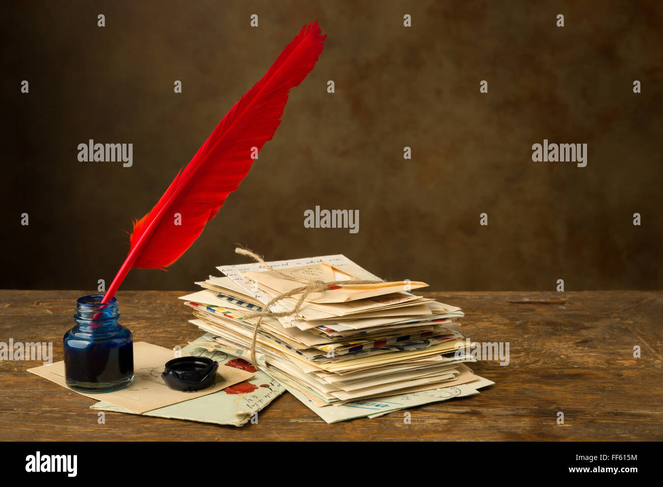 Red quill feather and ink well lying on an old table with nostalgic ...