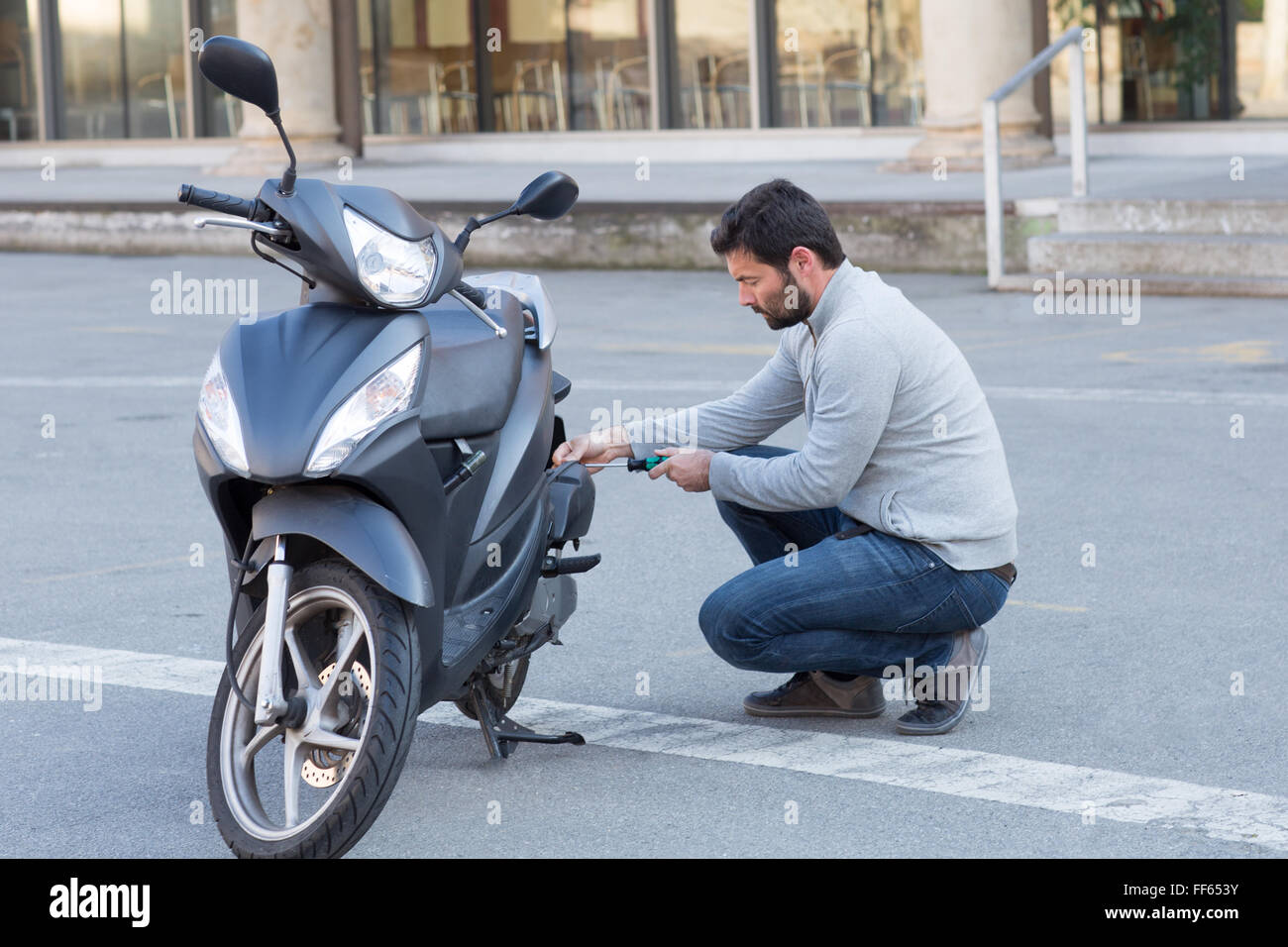 Man repairs a scooter Stock Photo - Alamy