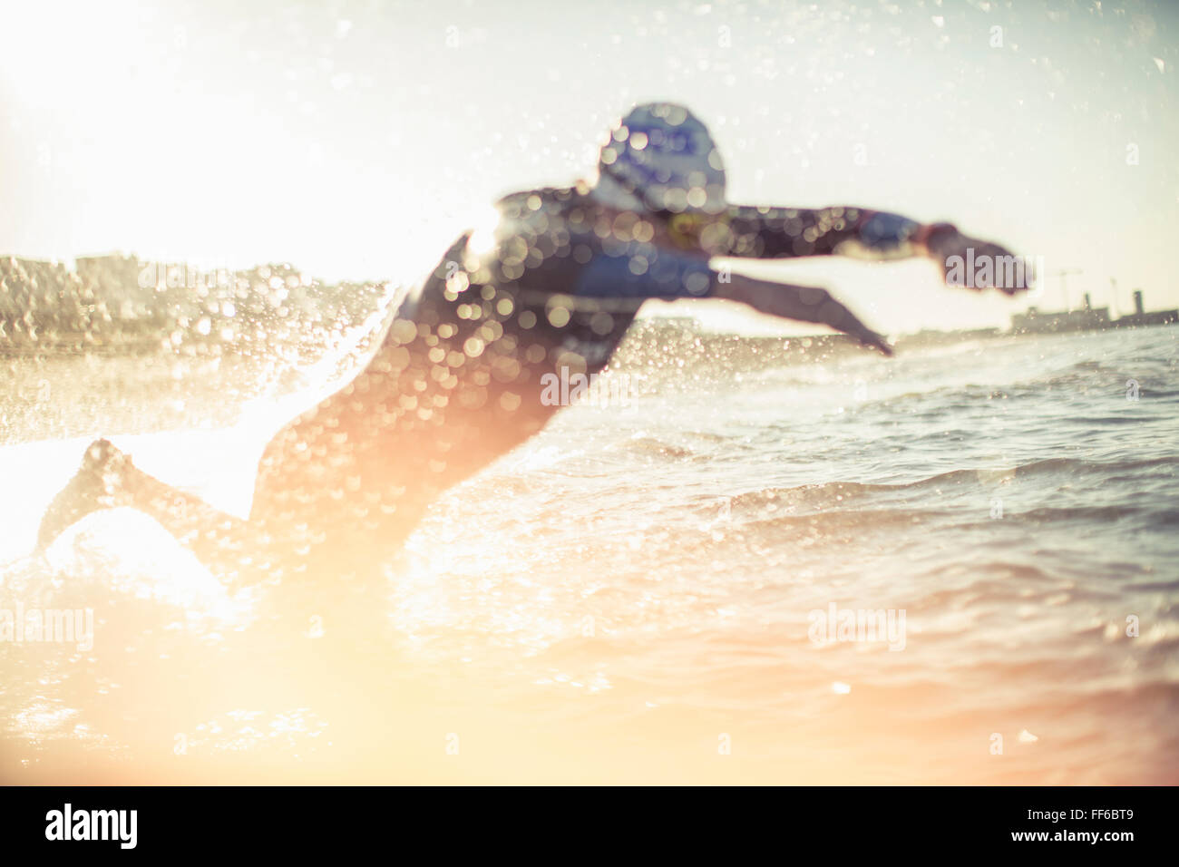 A swimmer in a wet suit running into the water, making a splash Stock ...