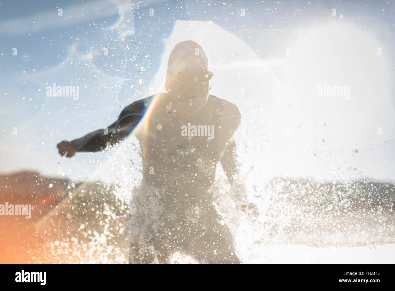 A swimmer in a wet suit running into the water, making a splash Stock ...