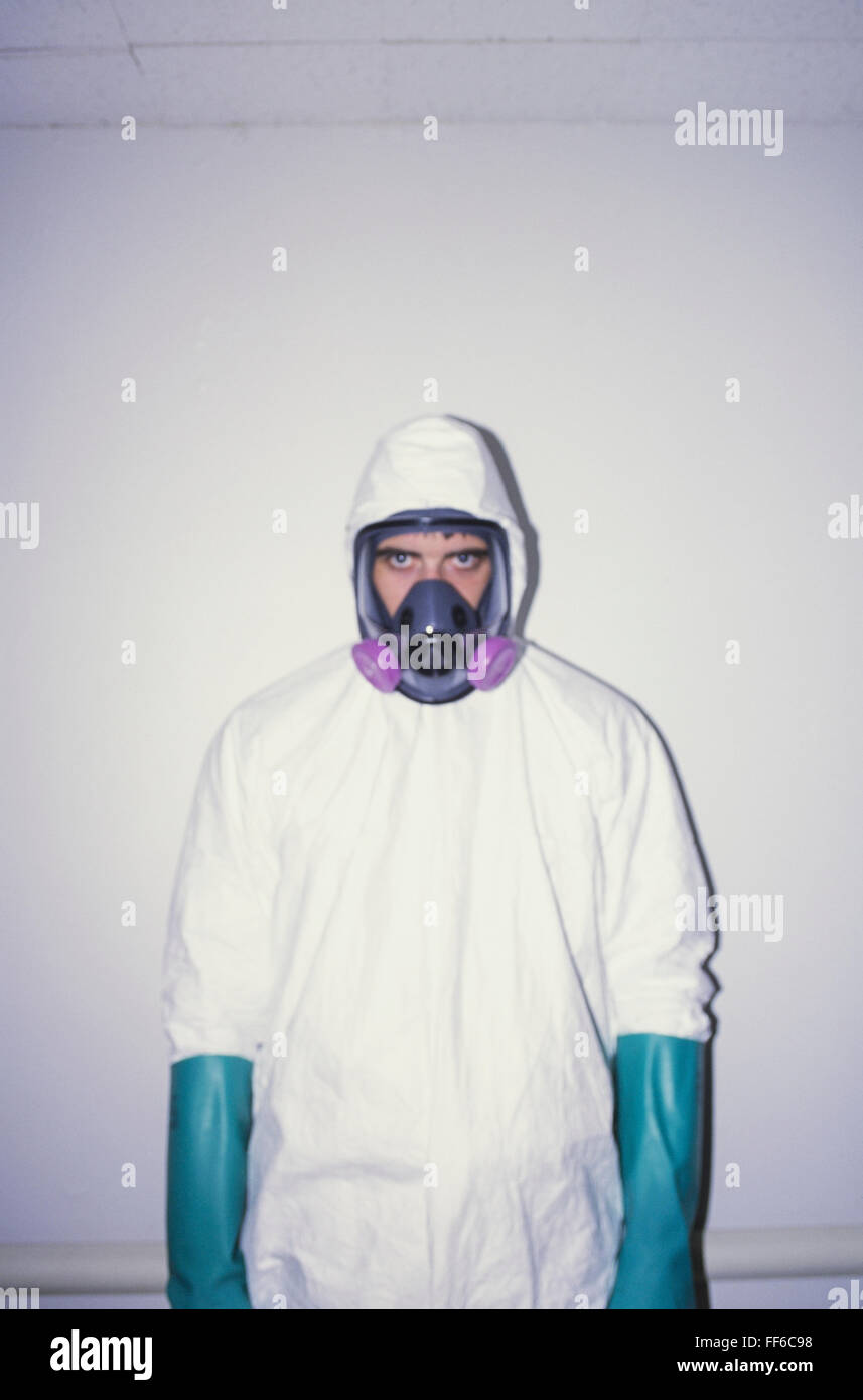 A man wearing a white protective clean suit and long thick blue gloves ...