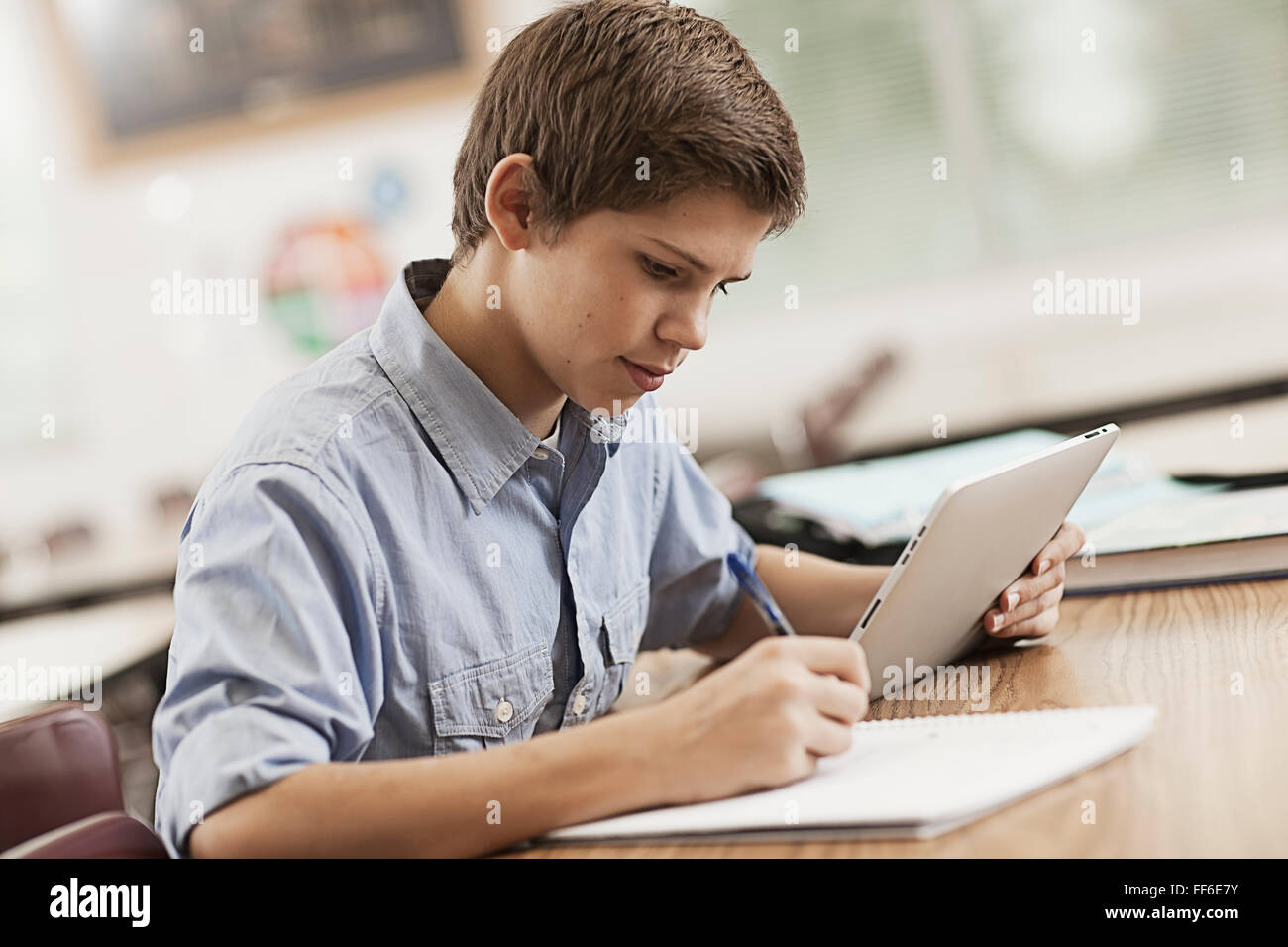 A boy sitting at a desk using a digital tablet Stock Photo - Alamy