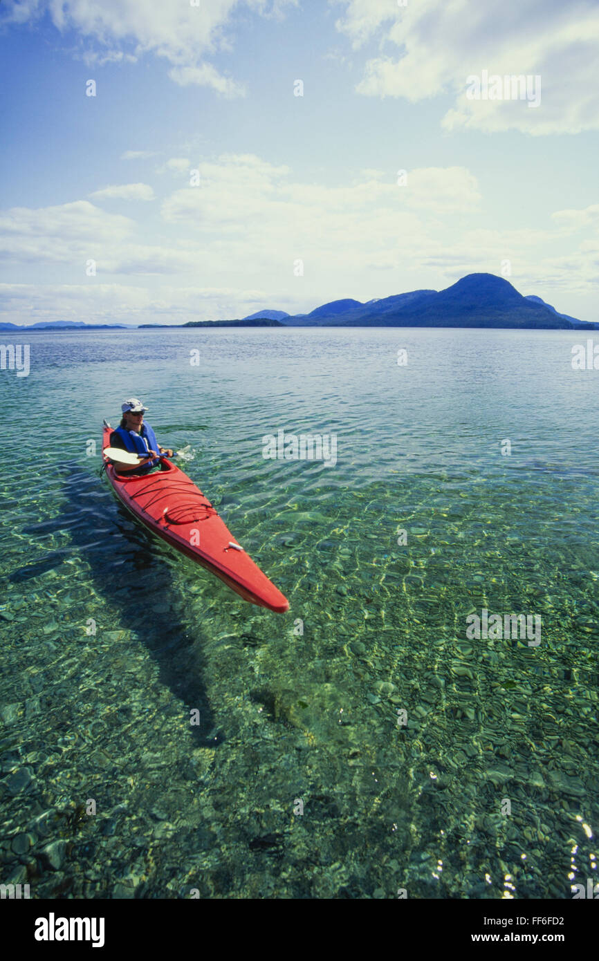 A man in a sea kayak on the clear calm waters off the shore of ...