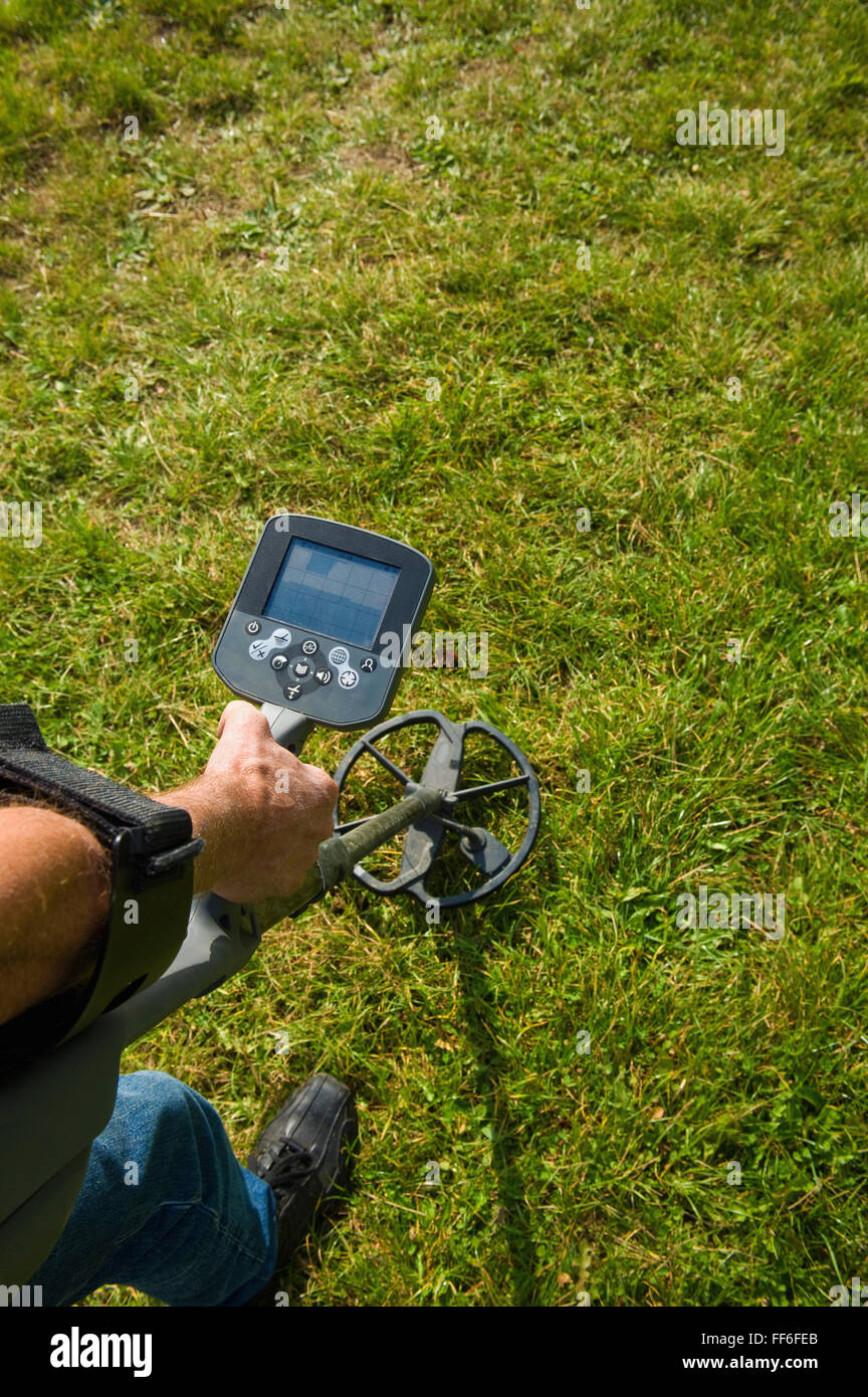A man's arm holdng a metal detector just about ground level, searching ...