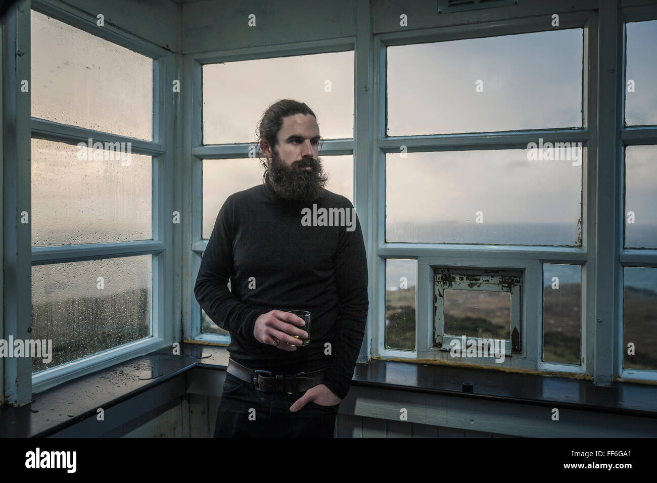 A man standing in a window holding a glass Stock Photo - Alamy