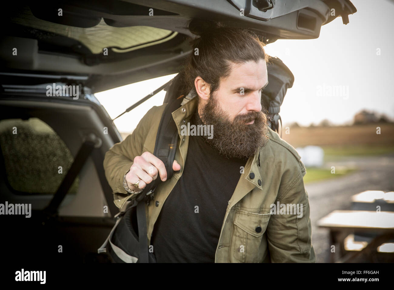 A man carrying a rucksack standing by an open car boot Stock Photo - Alamy