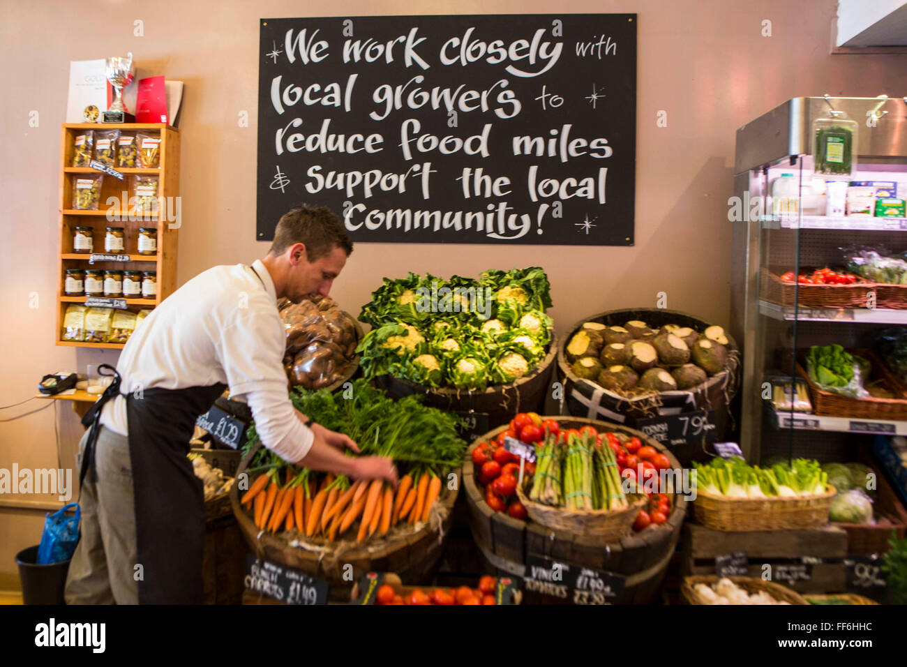A male shop keeper arranges the carrots in a fruit and vegetable ...