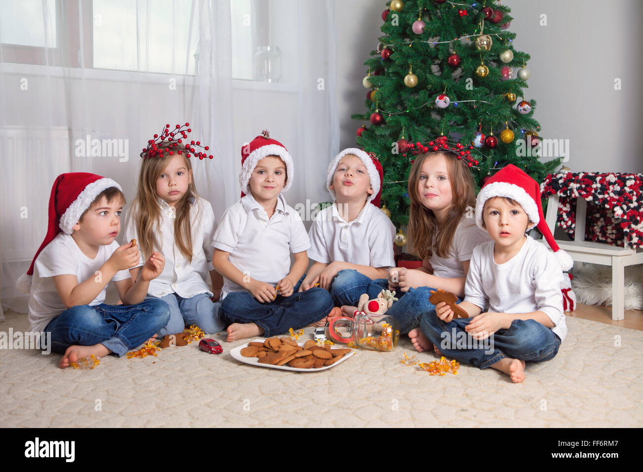 Six adorable children, having fun in front of the Christmas tree ...