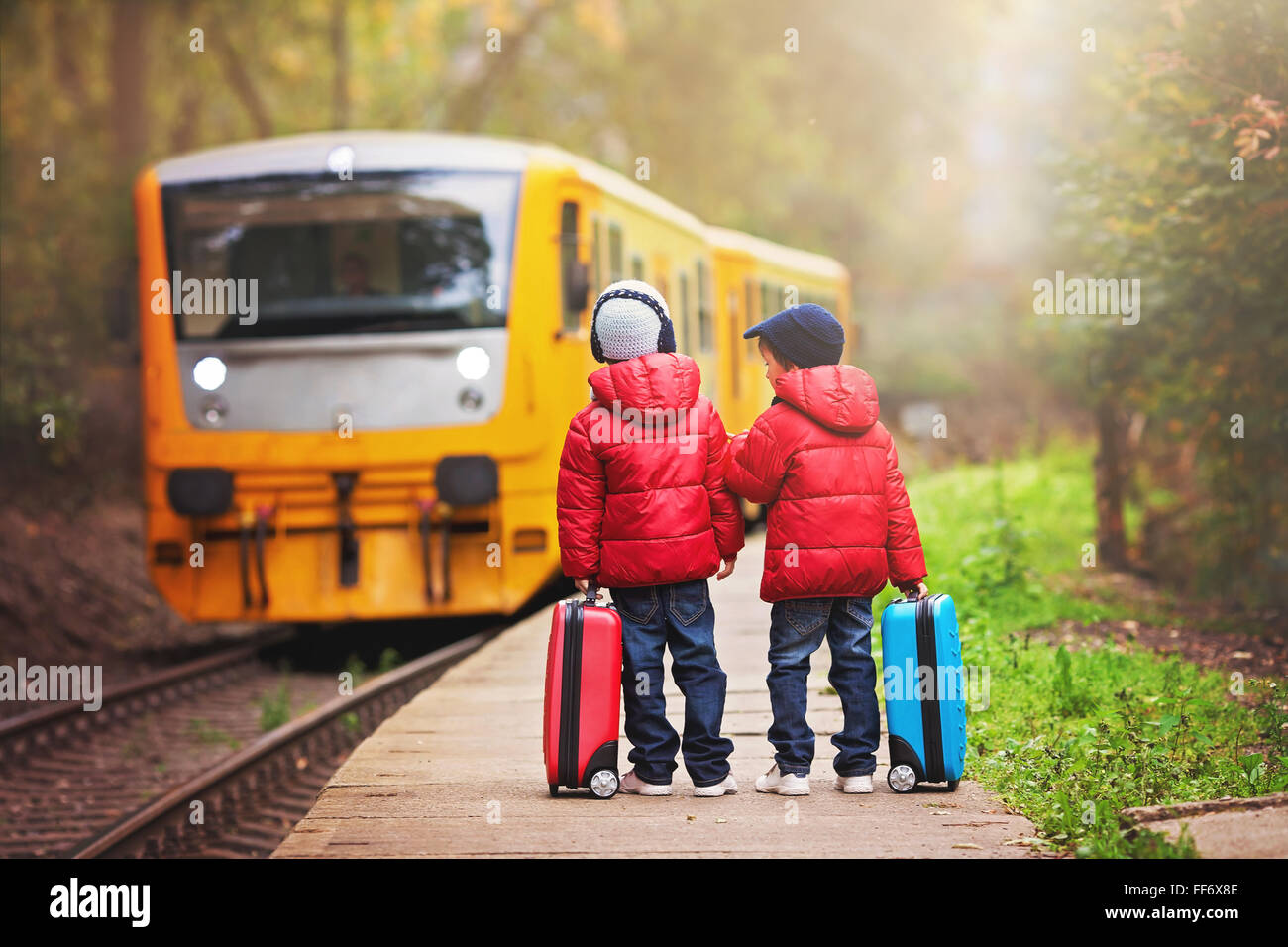 Two boys on a railway station, waiting for the train with suitcases ...