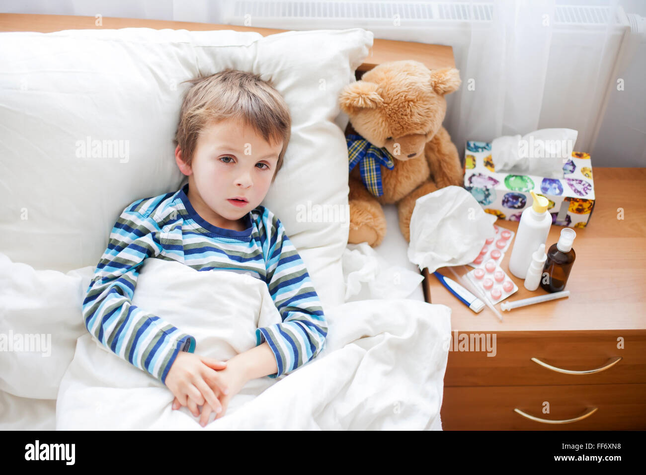Sick child boy lying in bed with a fever, resting at home Stock Photo ...