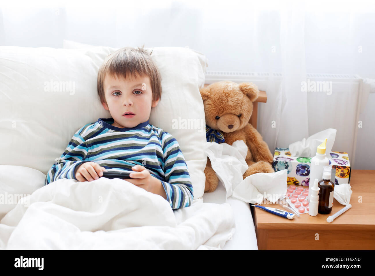 Sick child boy lying in bed with a fever, resting at home Stock Photo ...