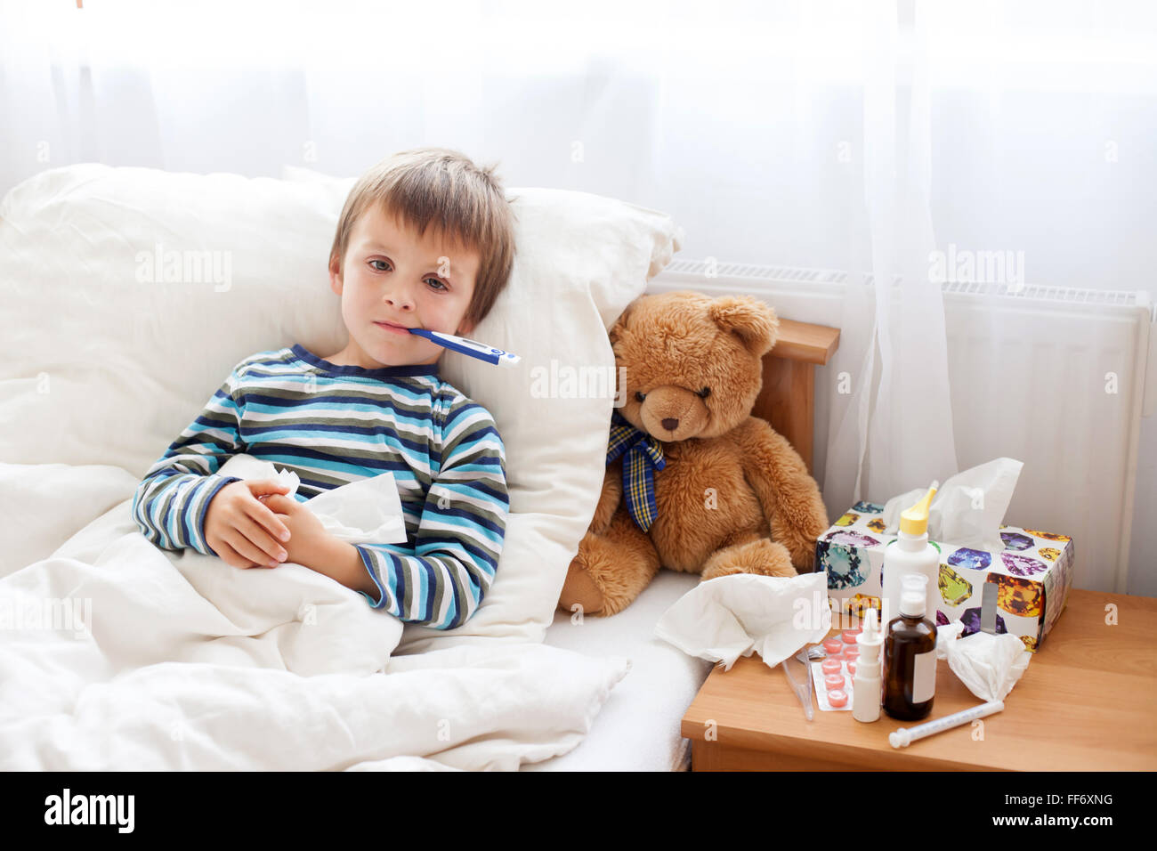 Sick child boy lying in bed with a fever, resting at home Stock Photo ...