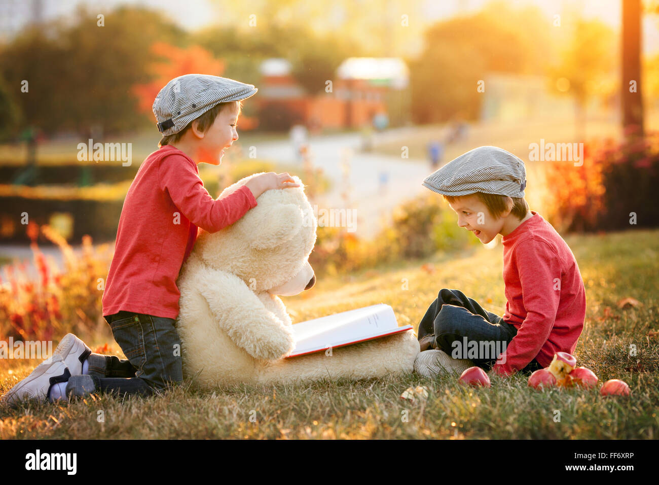 Two adorable little boys with his teddy bear friend in the park on ...