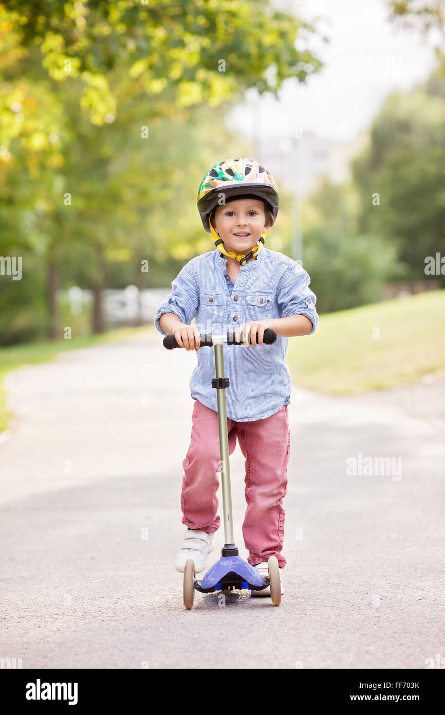 Cute boy, riding scooters, outdoor in the park, summertime on sunset ...