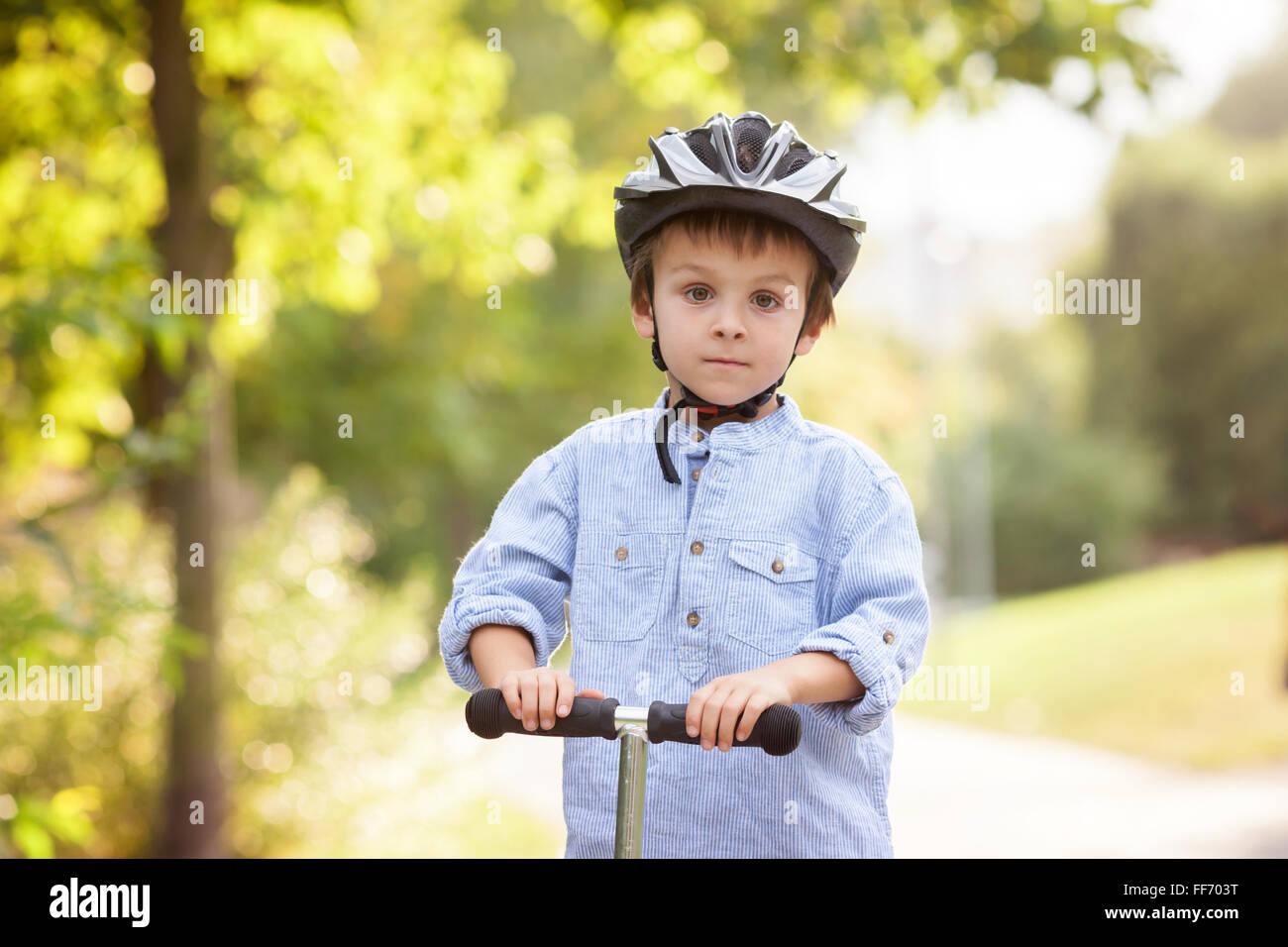 Cute boy, riding scooters, outdoor in the park, summertime on sunset ...
