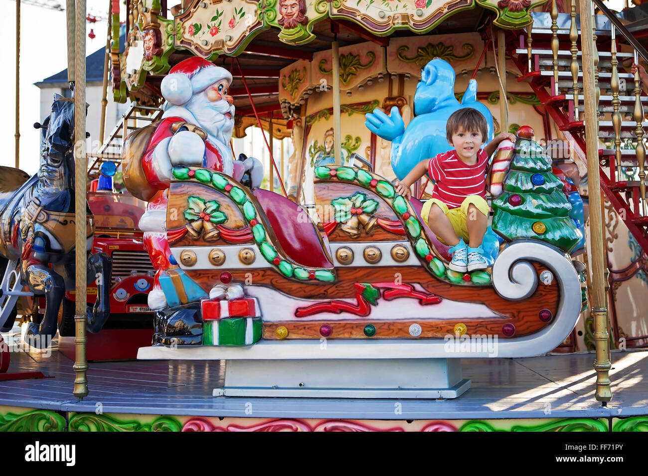 Sweet boy, riding in a Santa Claus sledge on a merry-go-round, carousel ...