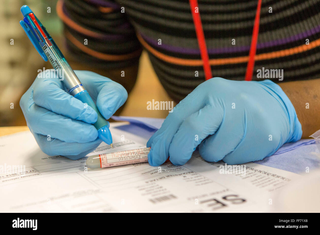 A nurse writes patients details on a blood sample bottle which will be ...