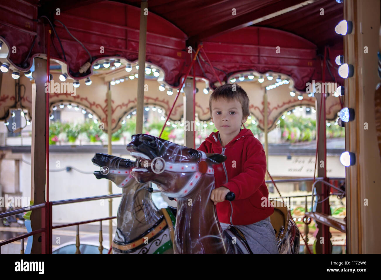 Sweet boy, riding in a train on a merry-go-round, carousel attraction ...