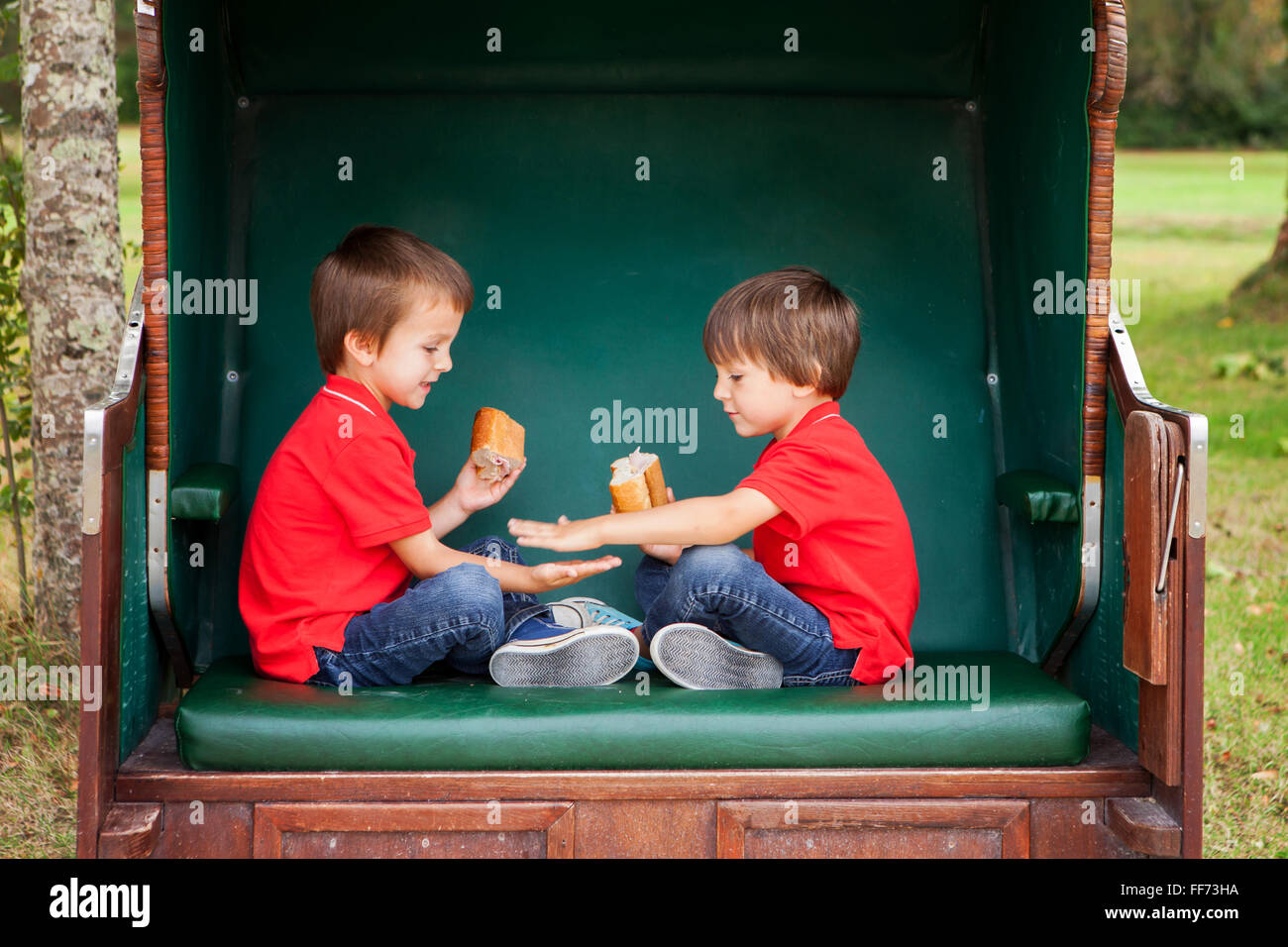 Two kids, sitting in a sheltered bench, playing hand clapping game and ...