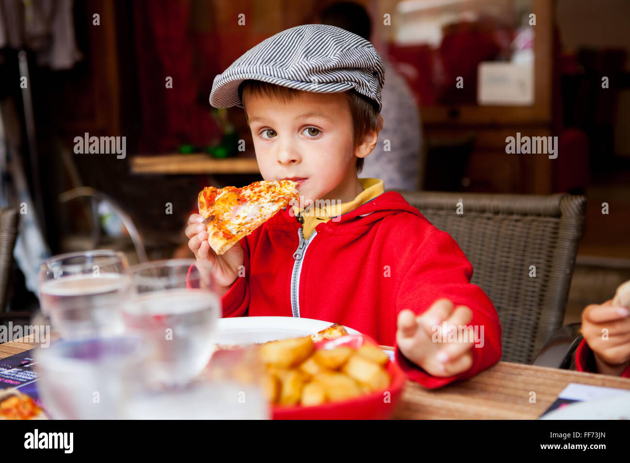 Sweet adorable child, boy, eating pizza at a restaurant, , summertime ...