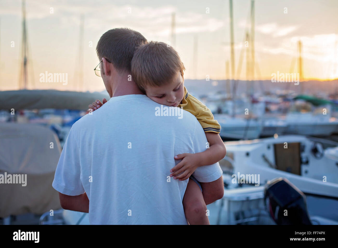 Father, holding his young child, while sleeping, enjoying the sunset ...