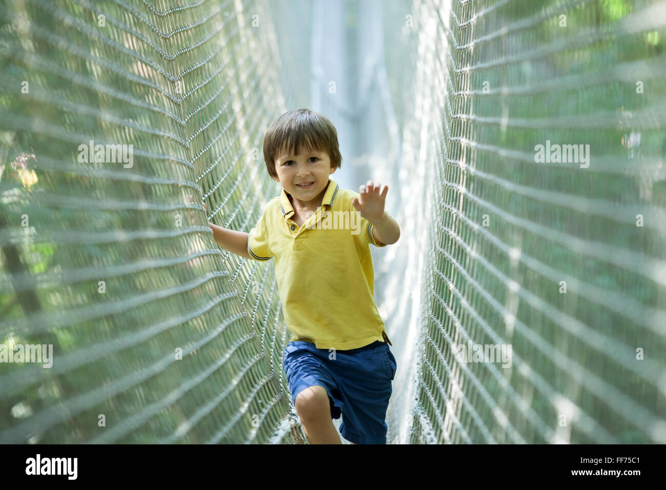 Cute child, boy, walking in a rope playground structure, rope web Stock ...