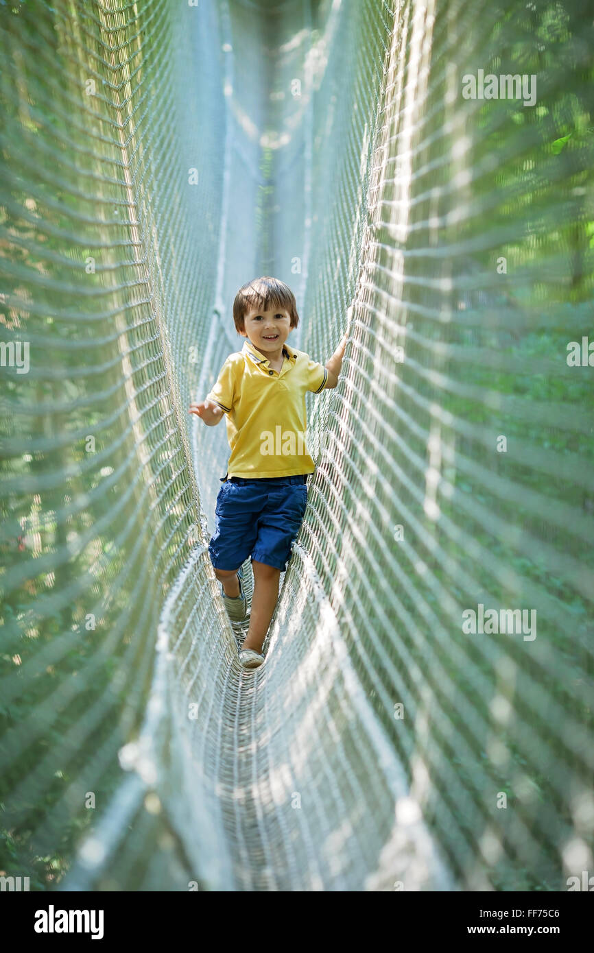 Cute child, boy, walking in a rope playground structure, rope web Stock ...