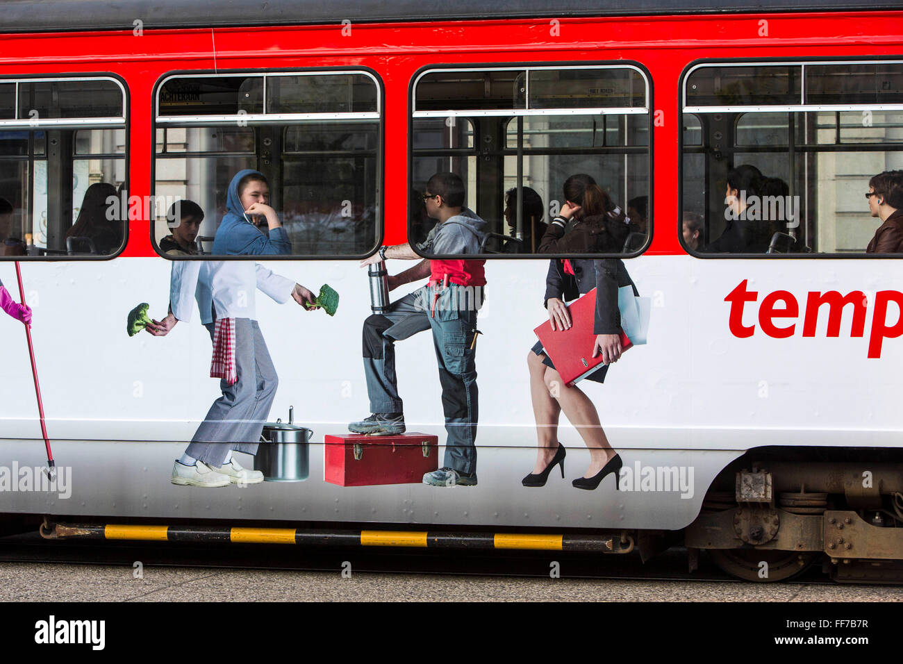 Side view of a De Lijn tram decorated with artwork of passengers legs ...