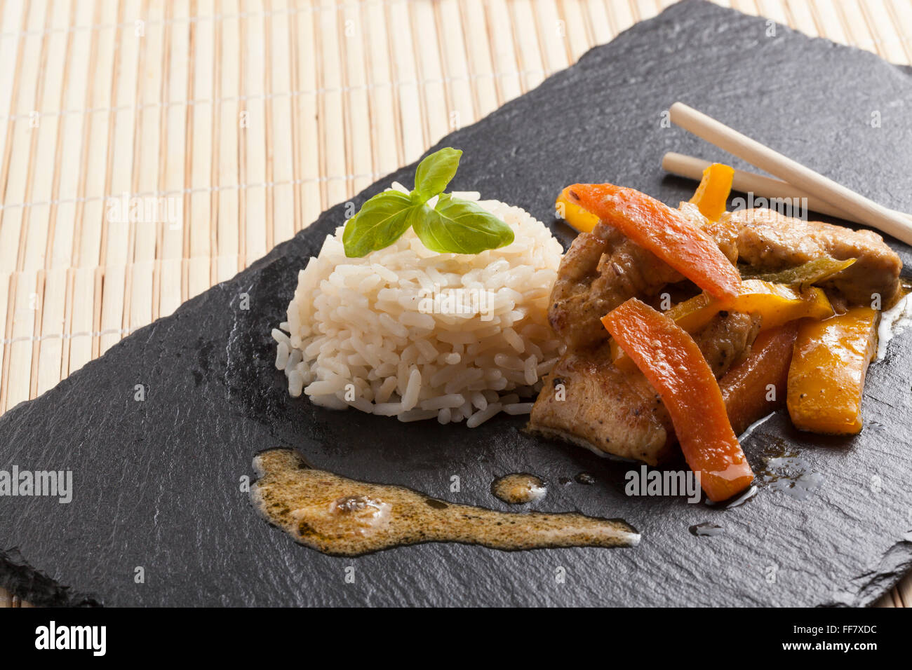 asian chicken dish on slate plate with rice Stock Photo - Alamy