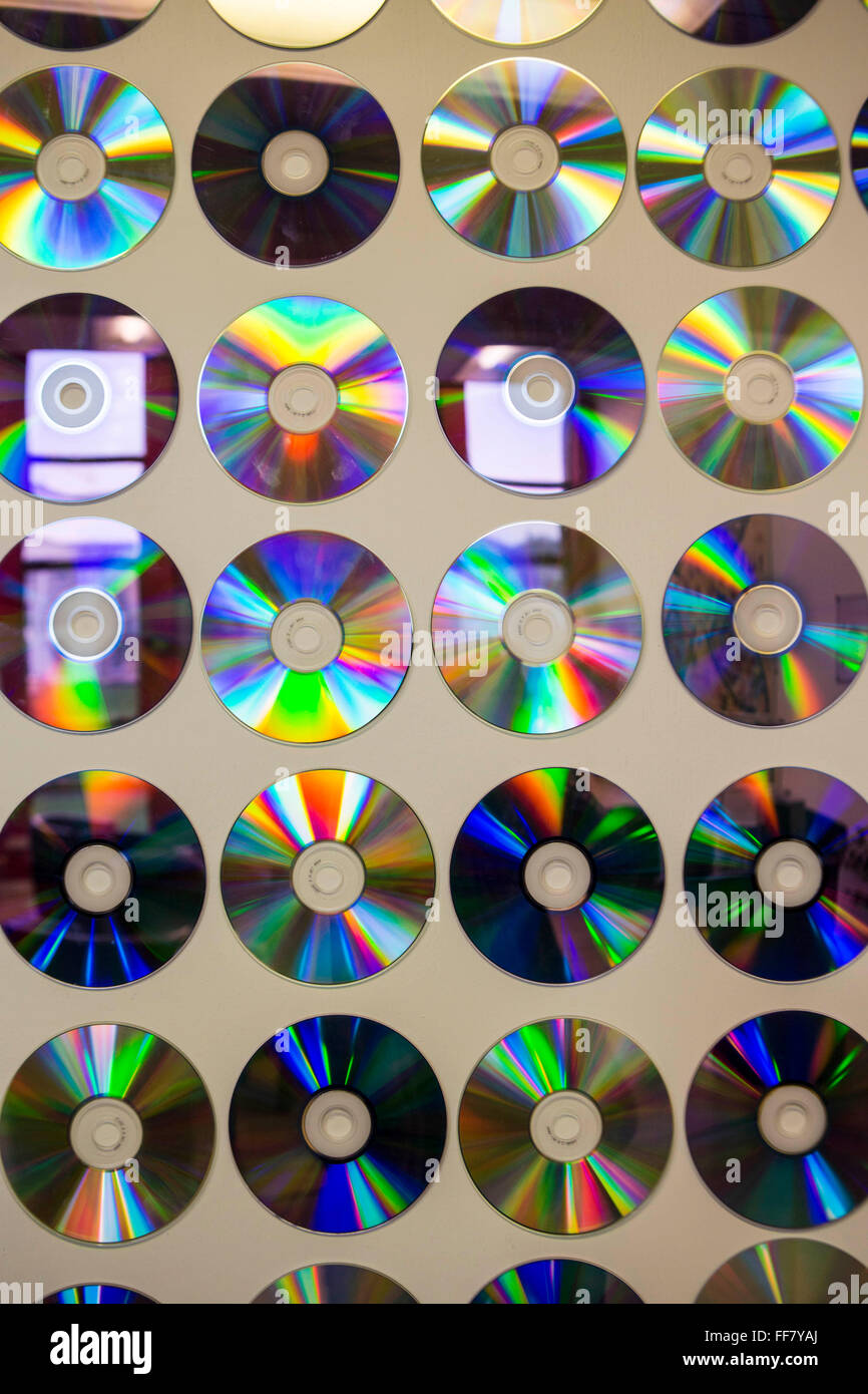 Multiple music compact disks hanging on a wall as part of a creative ...